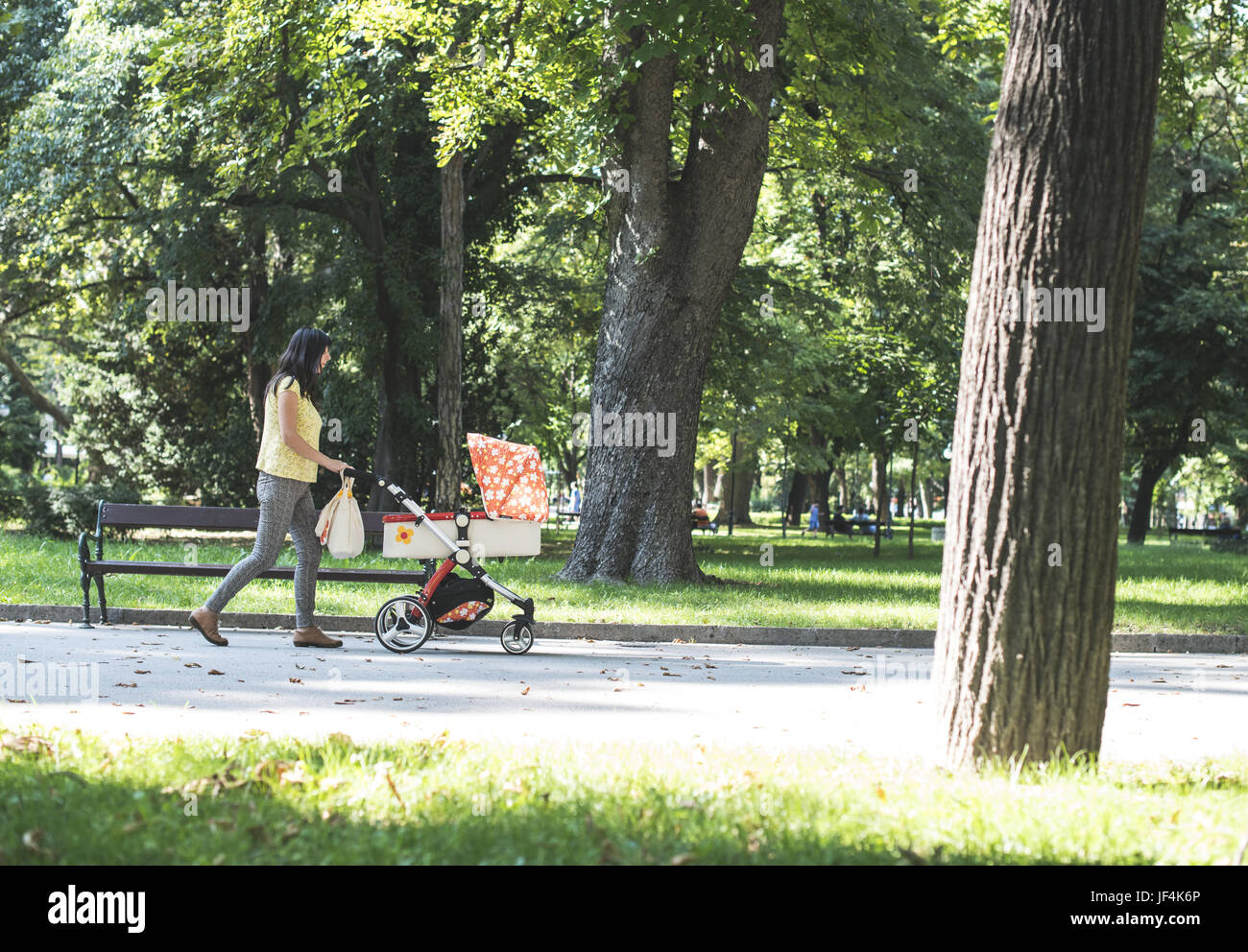 Mother walking in the park with baby buggy Stock Photo - Alamy
