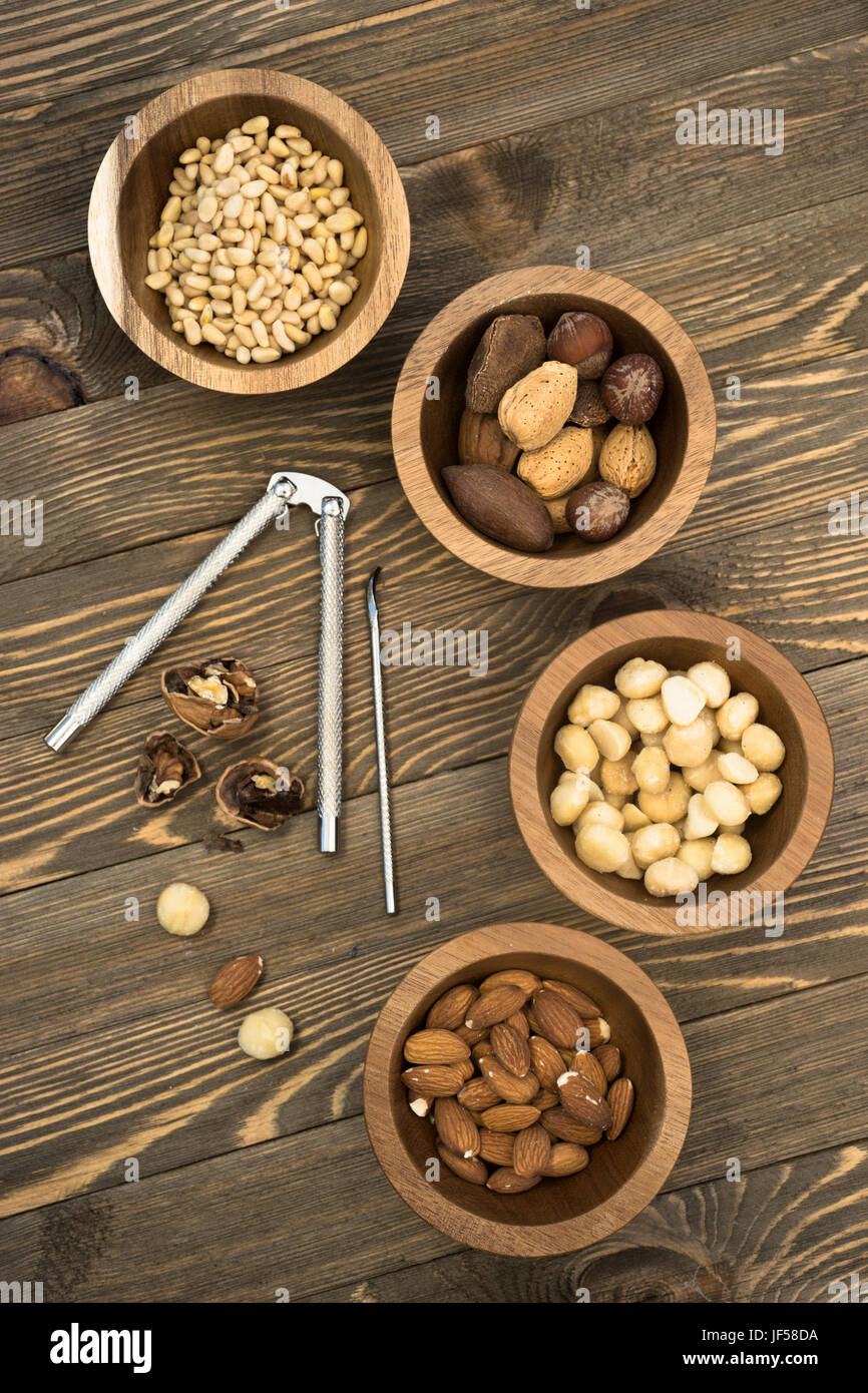 Utensils and nut filled bowls sit on wooden table Stock Photo - Alamy