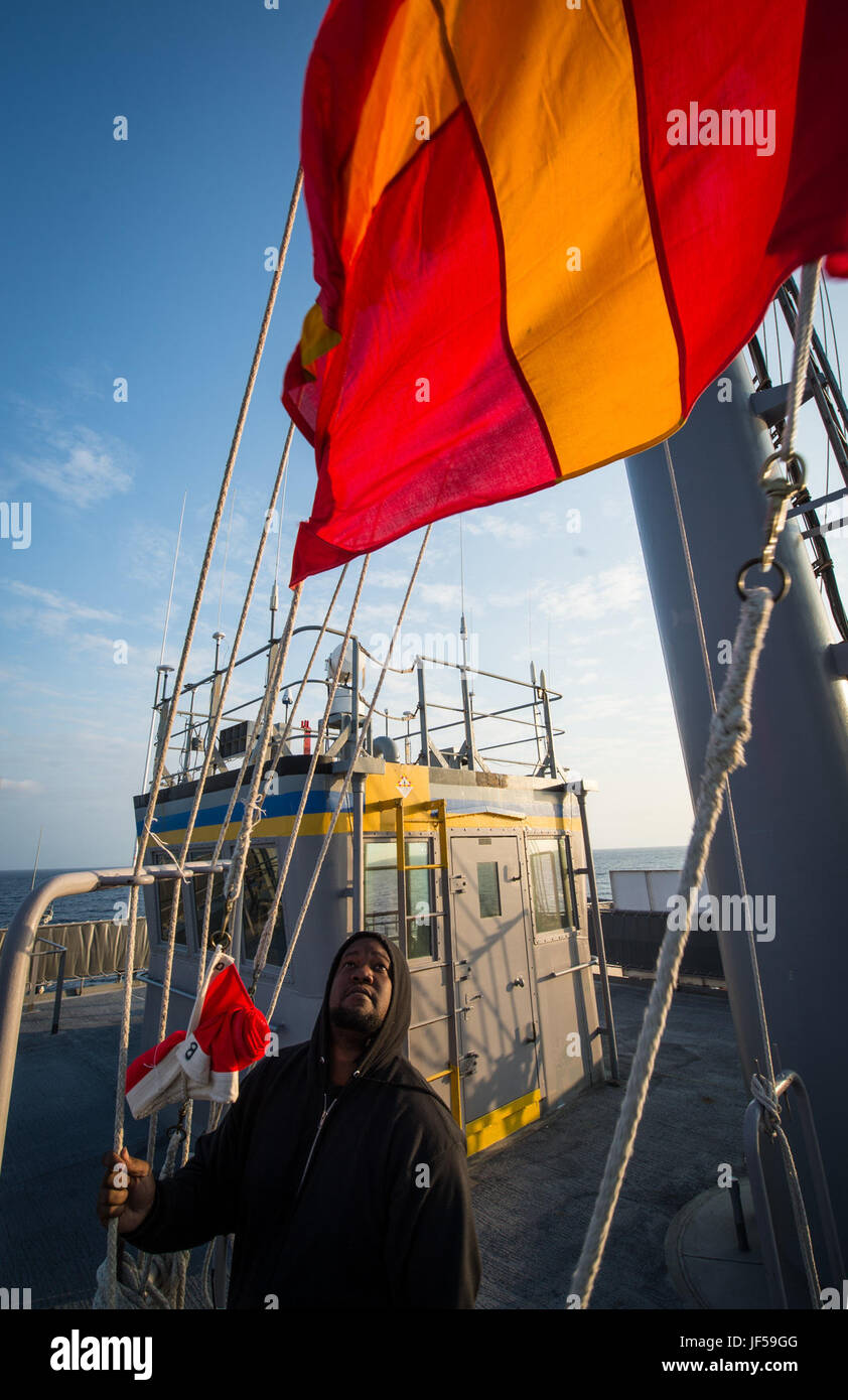 A mariner assigned to USNS Rappahannock (T-AO 204) hoist a flag as the ...
