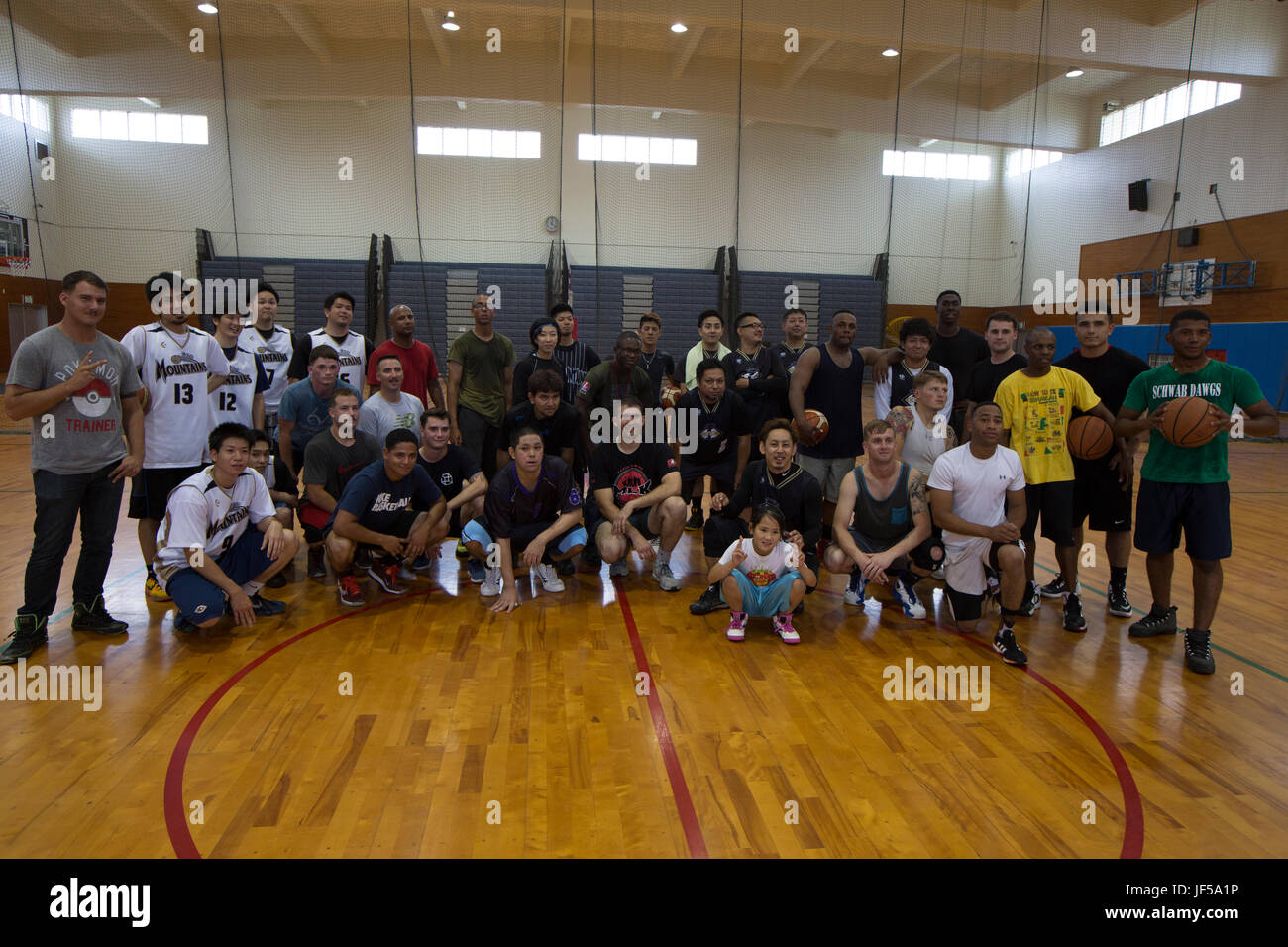 Players, referees and scorekeepers pose for a photo during a basketball ...
