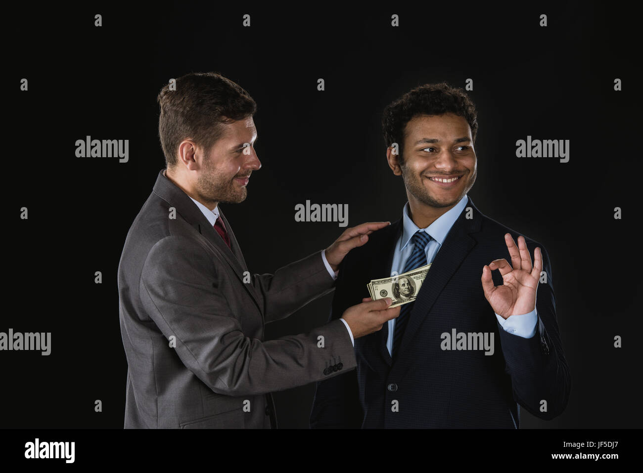 Businessman giving money and bribing business partner isolated on black ...