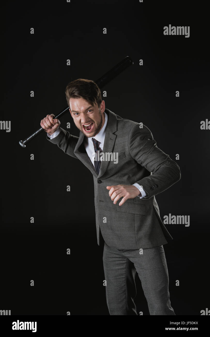 Angry businessman holding baseball bat and screaming isolated on black ...