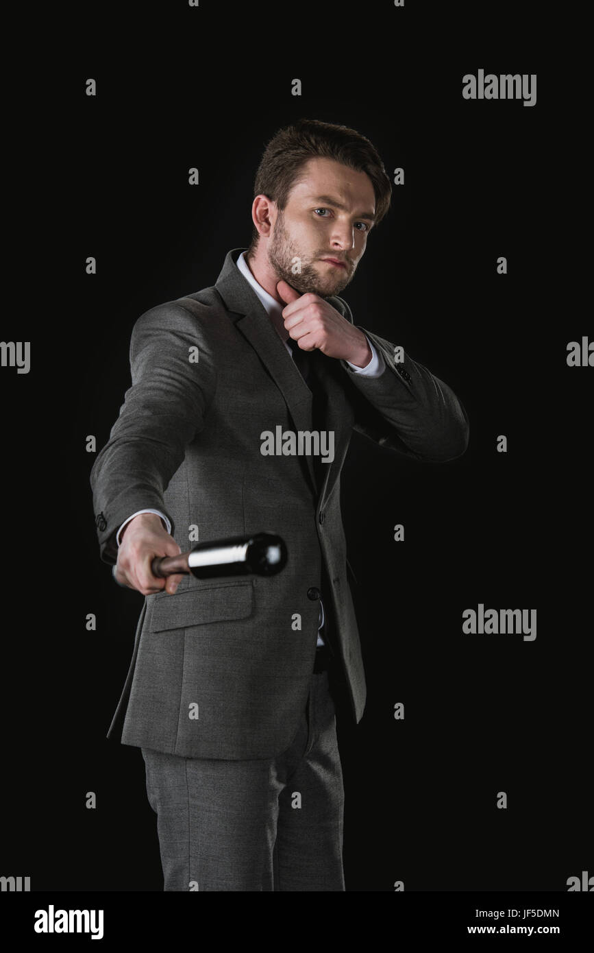 Serious businessman holding baseball bat and gesturing with thumb on ...