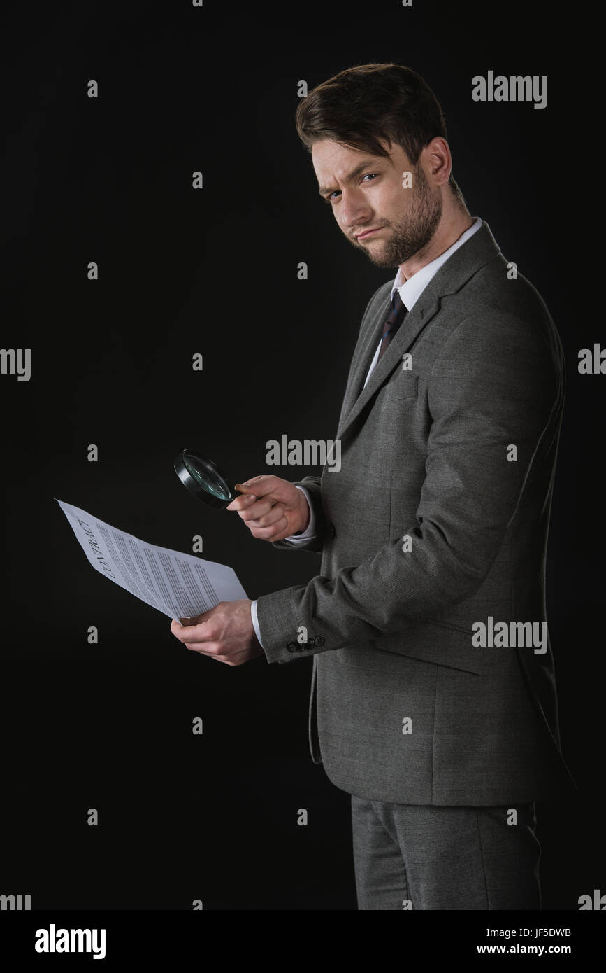 side view of businessman with magnifying glass holding contract ...