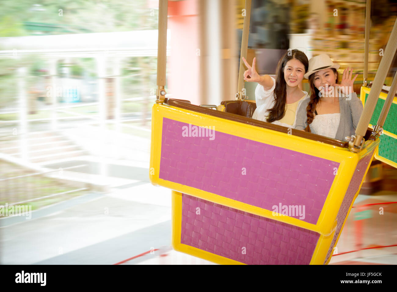 cheerful asian female friends playing the rotation fast flying chair ...