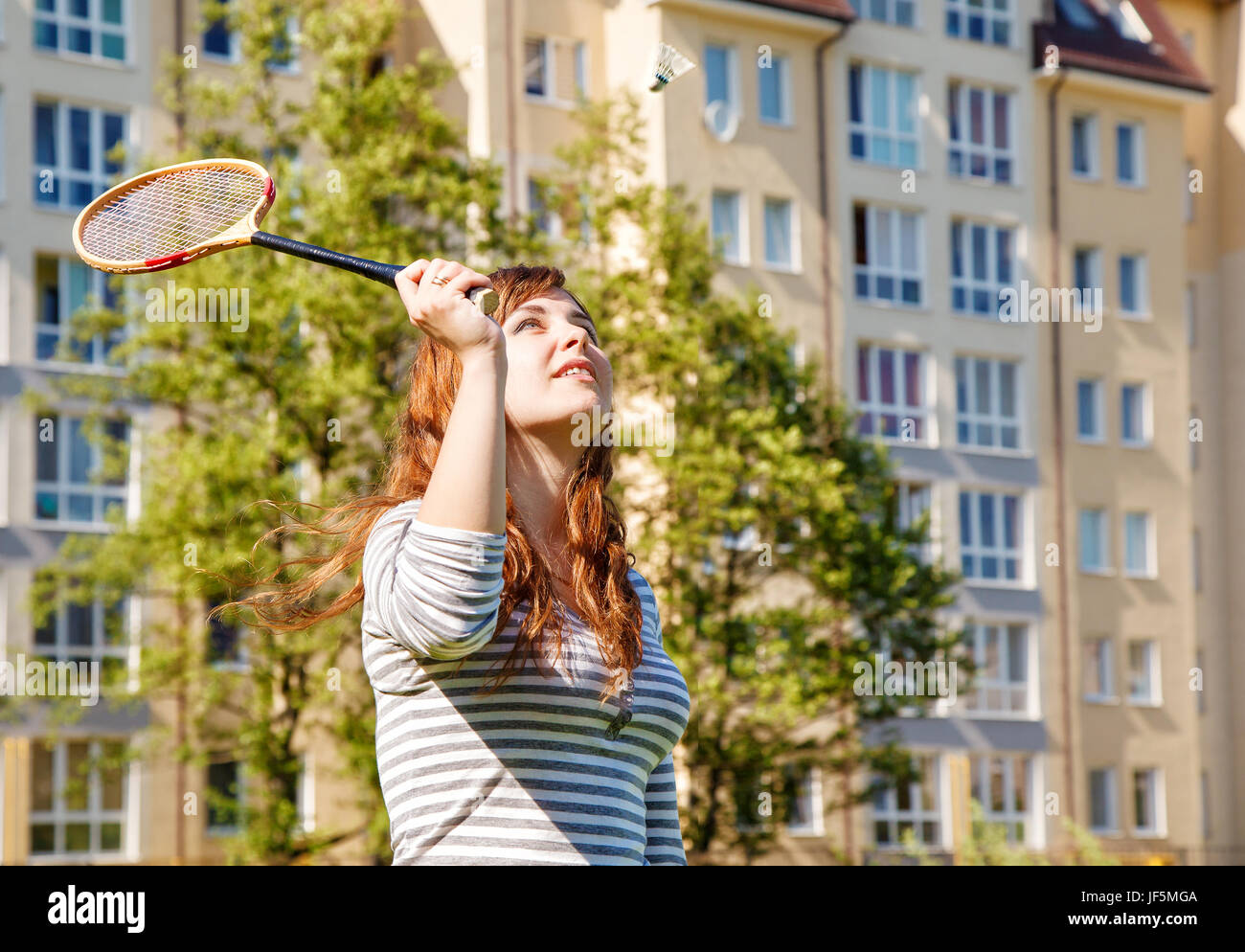 young beautiful woman playing badminton in the park on sunny summer day ...