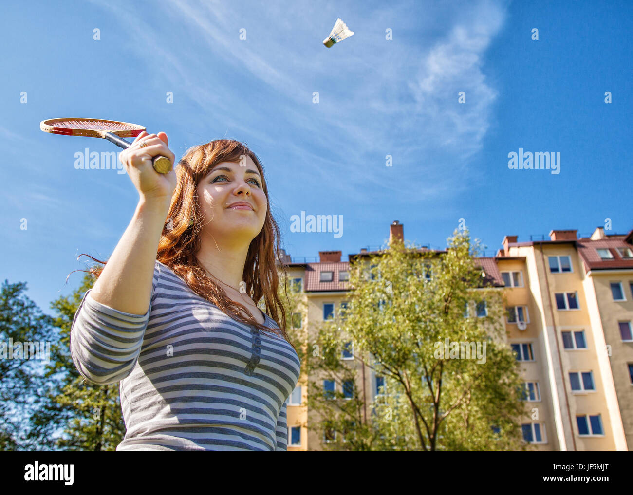 young beautiful woman playing badminton in the park on sunny summer day ...