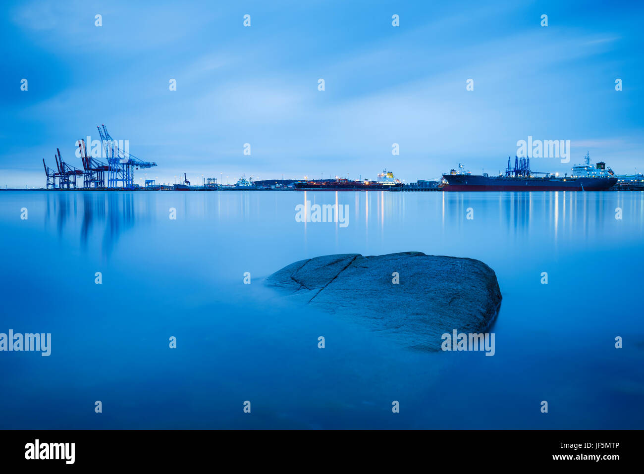 Rock in water, shipping docks on background Stock Photo - Alamy