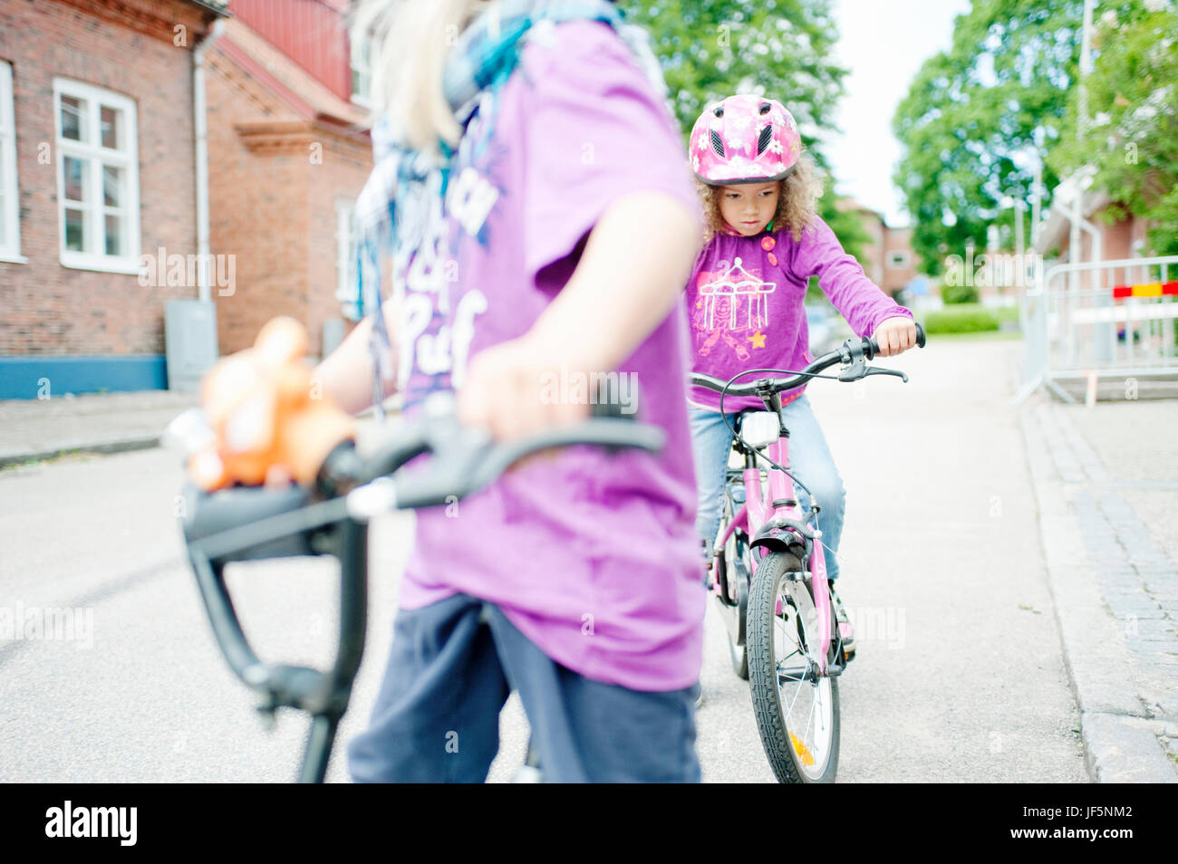 Two girls cycling in street Stock Photo - Alamy
