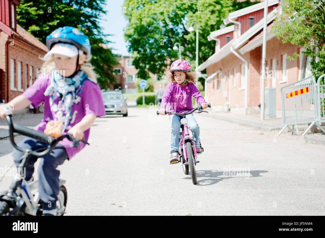 Two girls cycling in street Stock Photo - Alamy