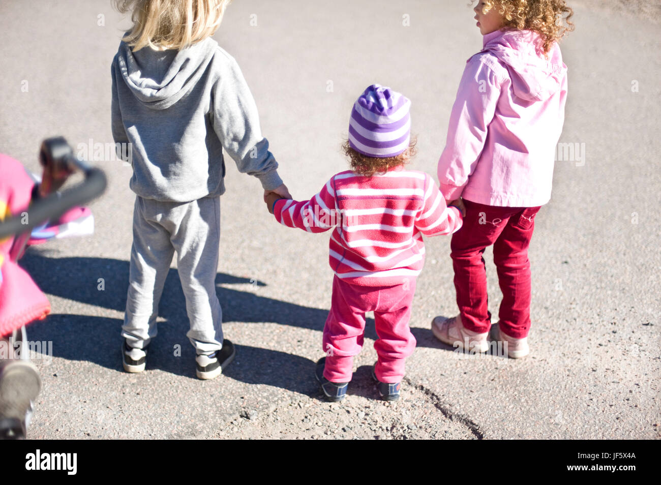 Three girls holding hands Stock Photo - Alamy