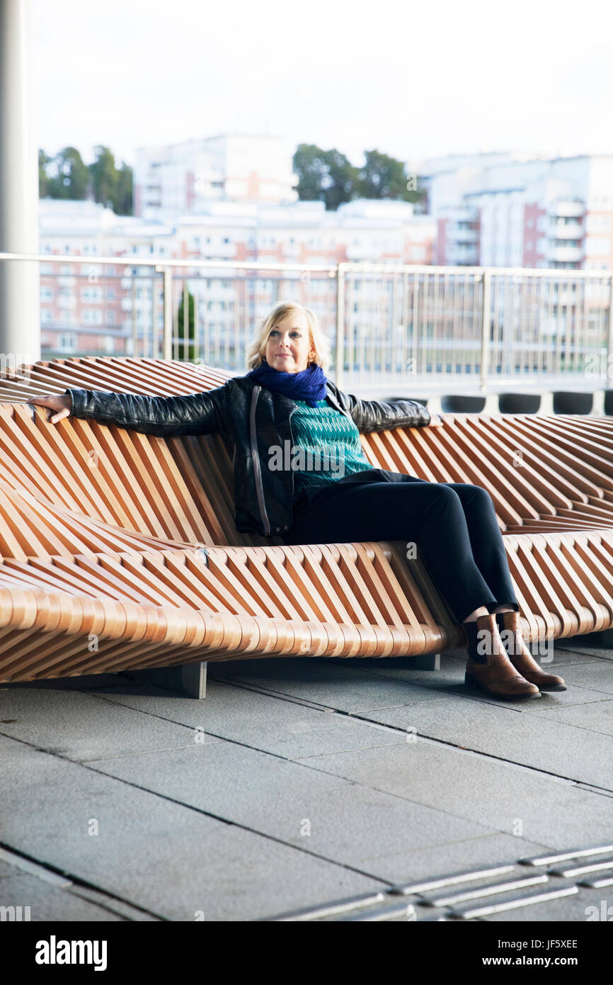 Woman sitting on modern bench Stock Photo - Alamy