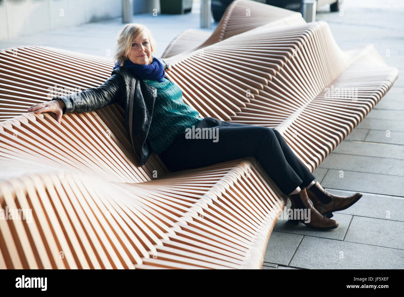 Woman sitting on modern bench Stock Photo - Alamy