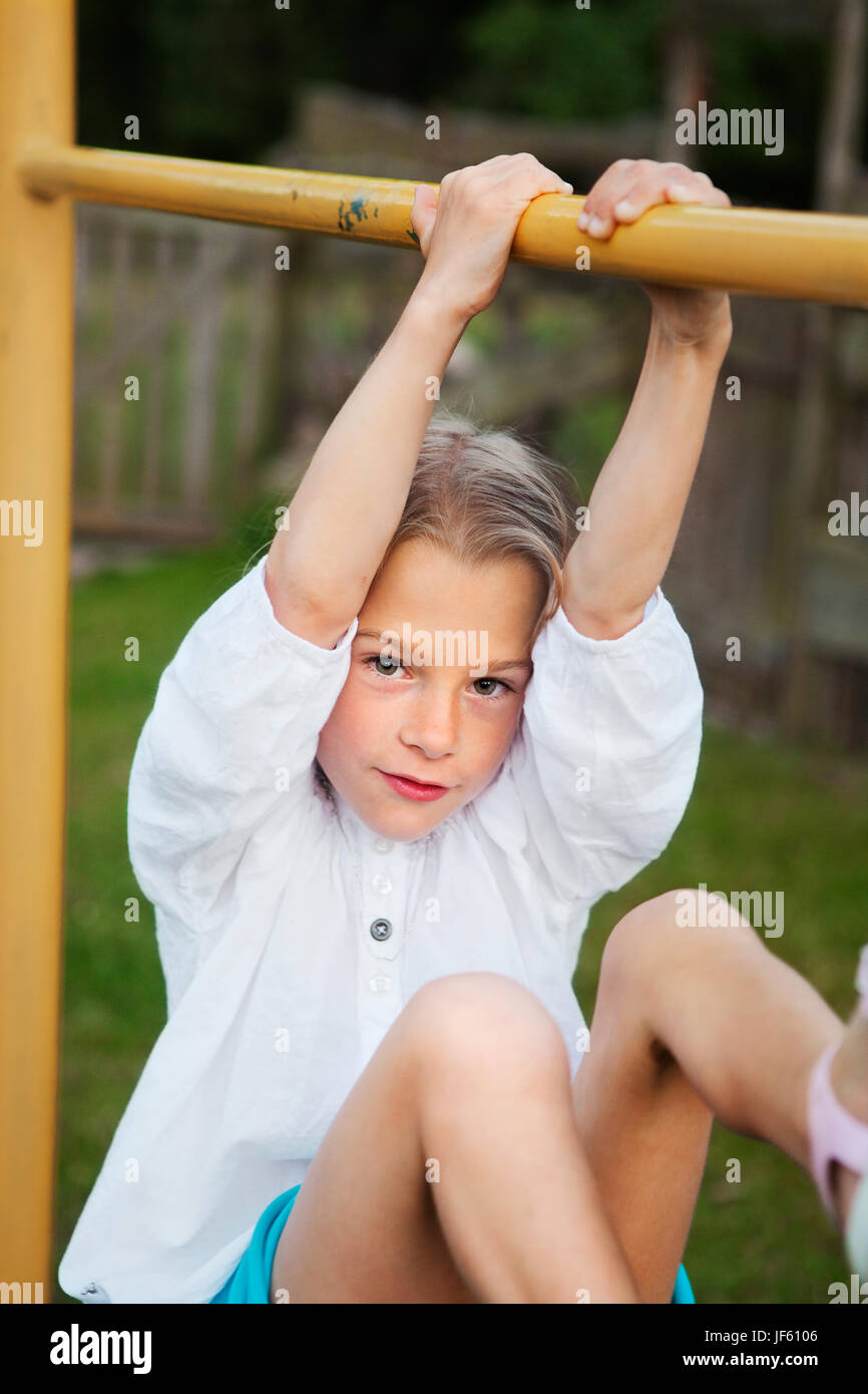 Girl hanging on metal bar Stock Photo - Alamy