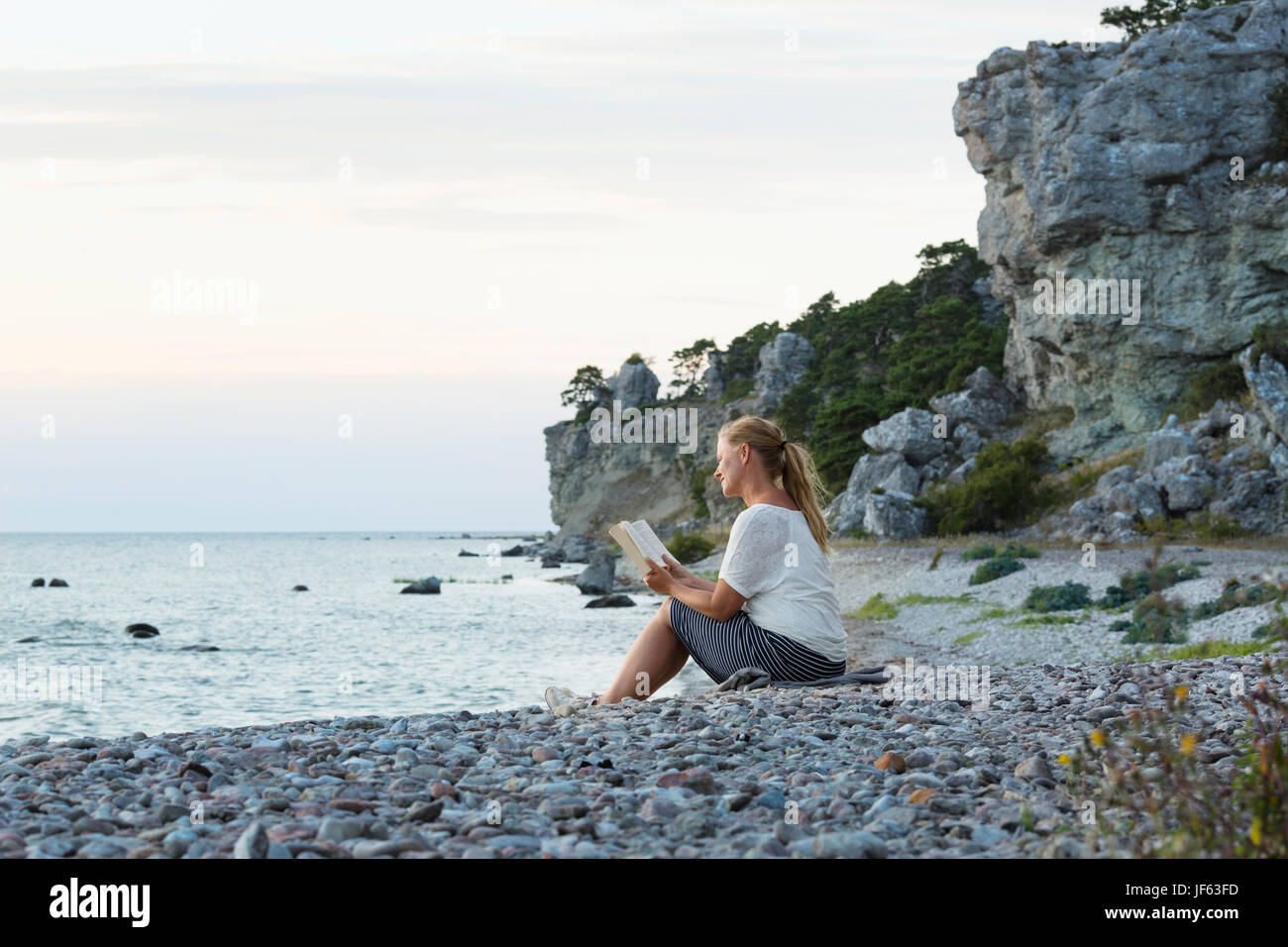 Woman reading on beach Stock Photo - Alamy