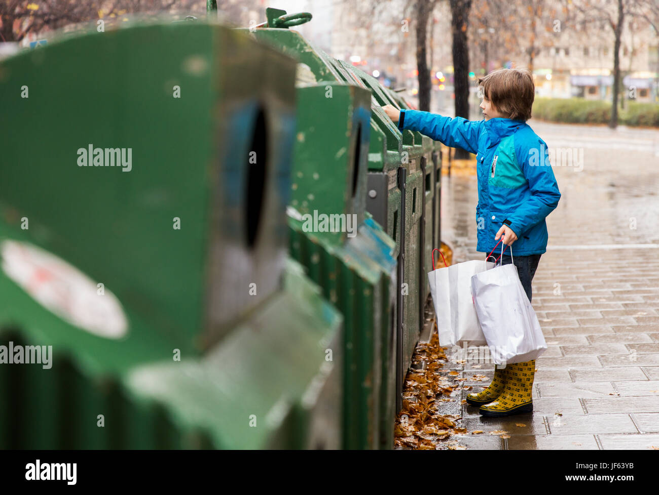 Boy putting waste into recycling bin Stock Photo - Alamy
