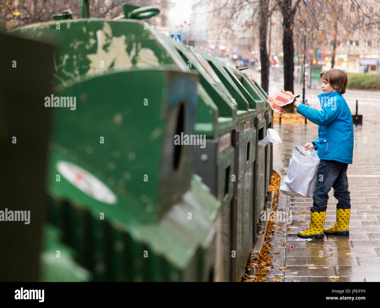Boy putting waste into recycling bin Stock Photo - Alamy