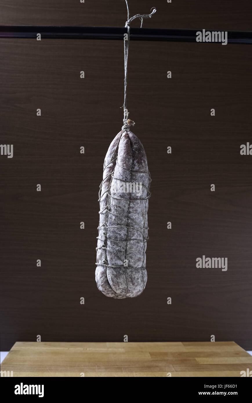 Salami hanging on wood background Stock Photo - Alamy