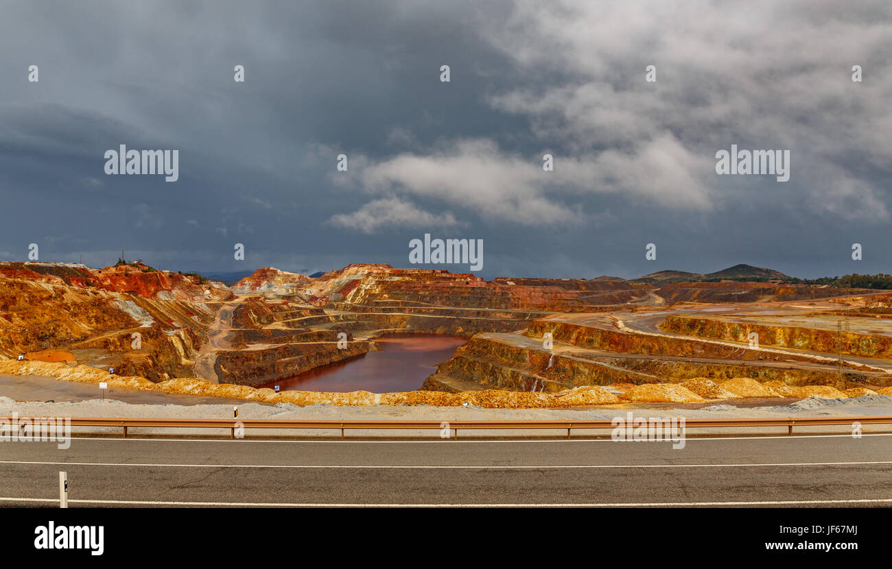 Wide angle view of copper mine open pit in Rio Tinto with road, cloudy ...