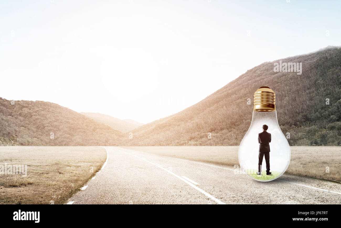 Young businessman trapped inside of light bulb on asphalt road Stock ...