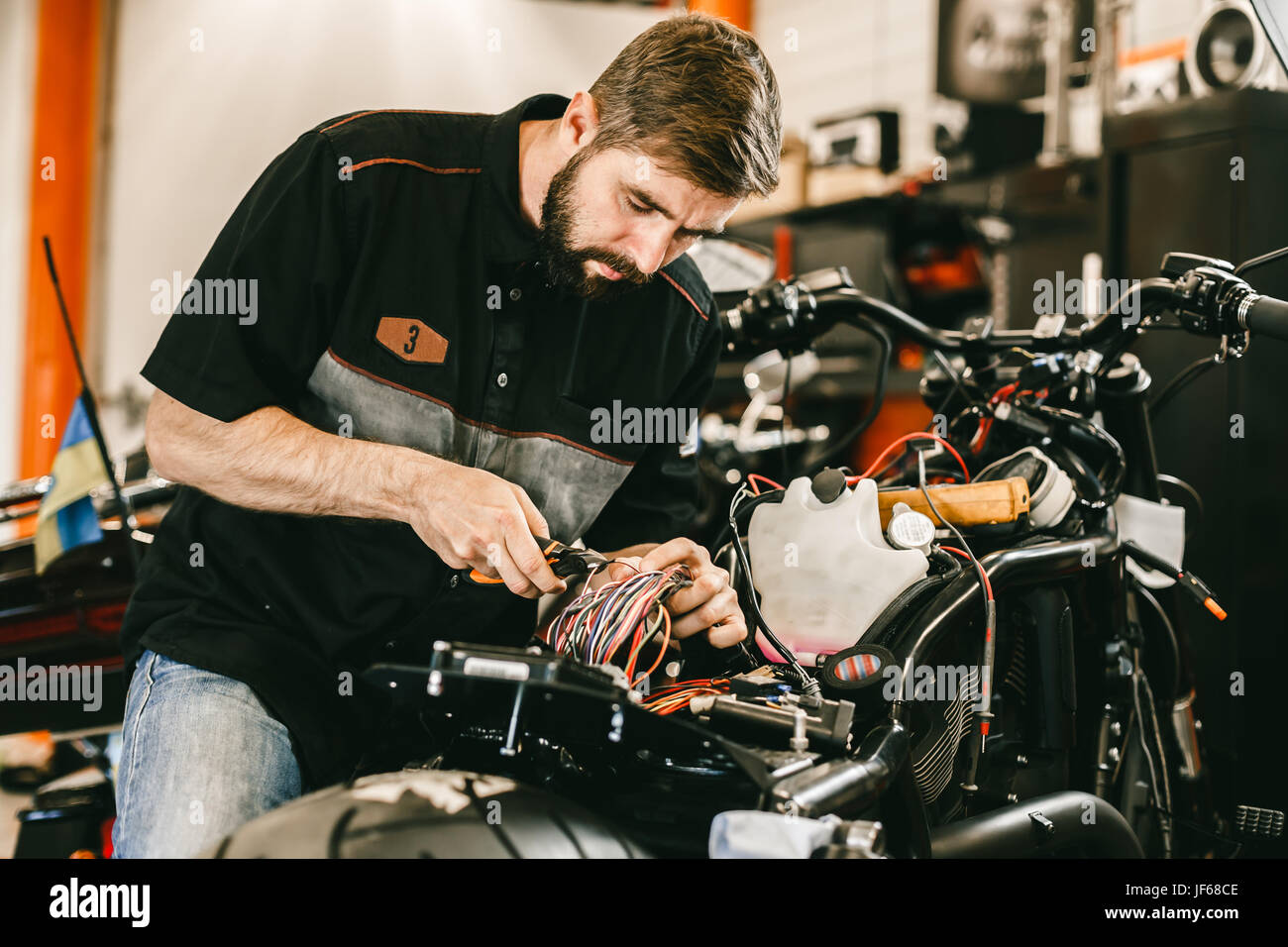 Professional motorcycle mechanic works with electronics, cuts wires ...
