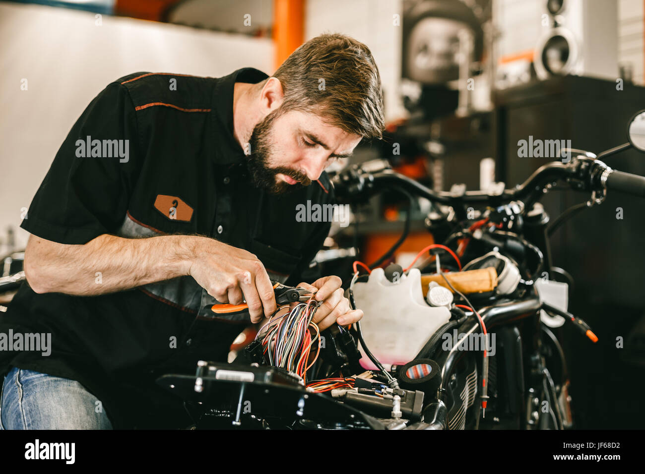 Professional motorcycle mechanic works with electronics, cuts wires ...