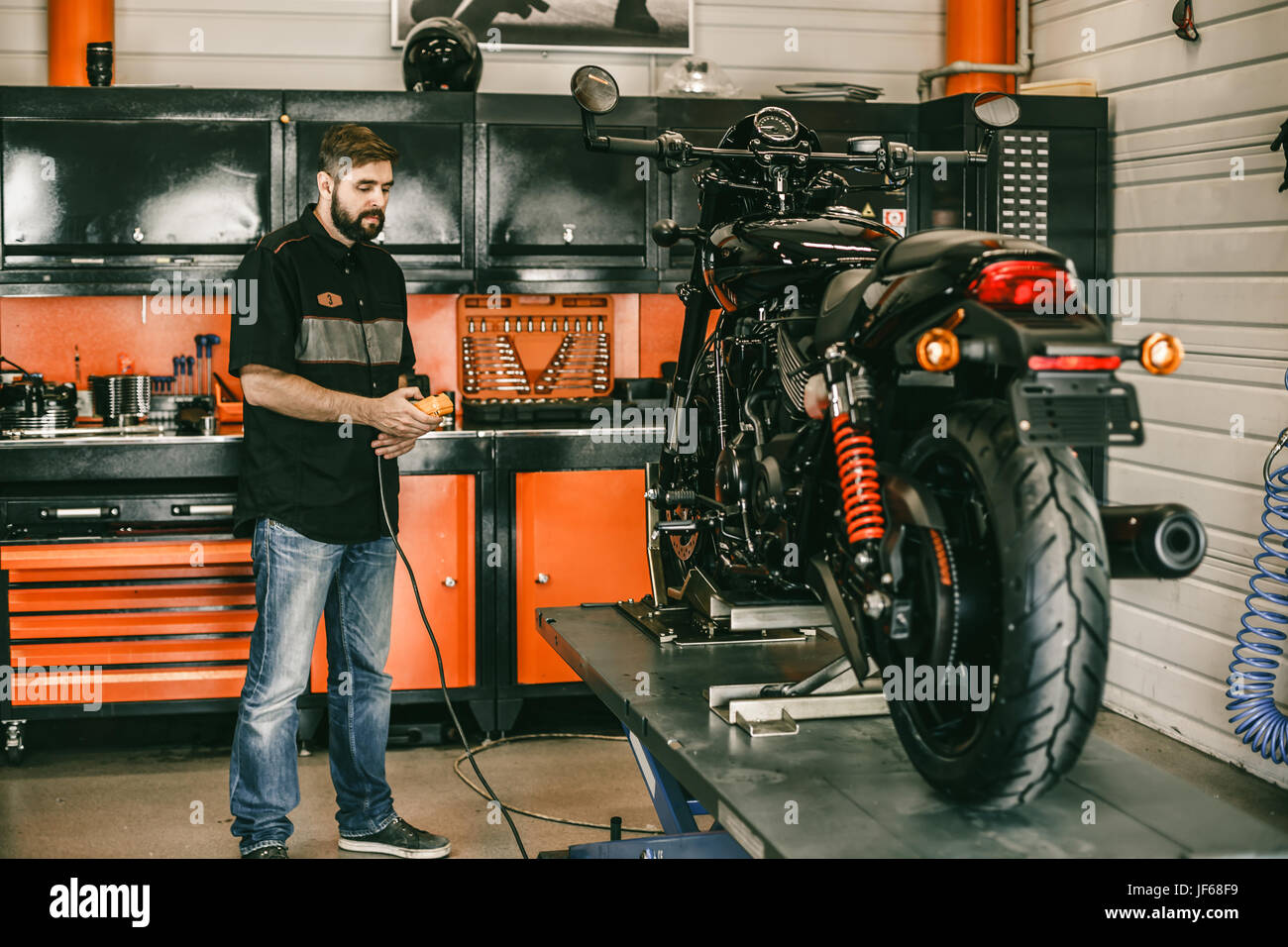 Professional moto mechanic raises a motorcycle on the lift. Man ...