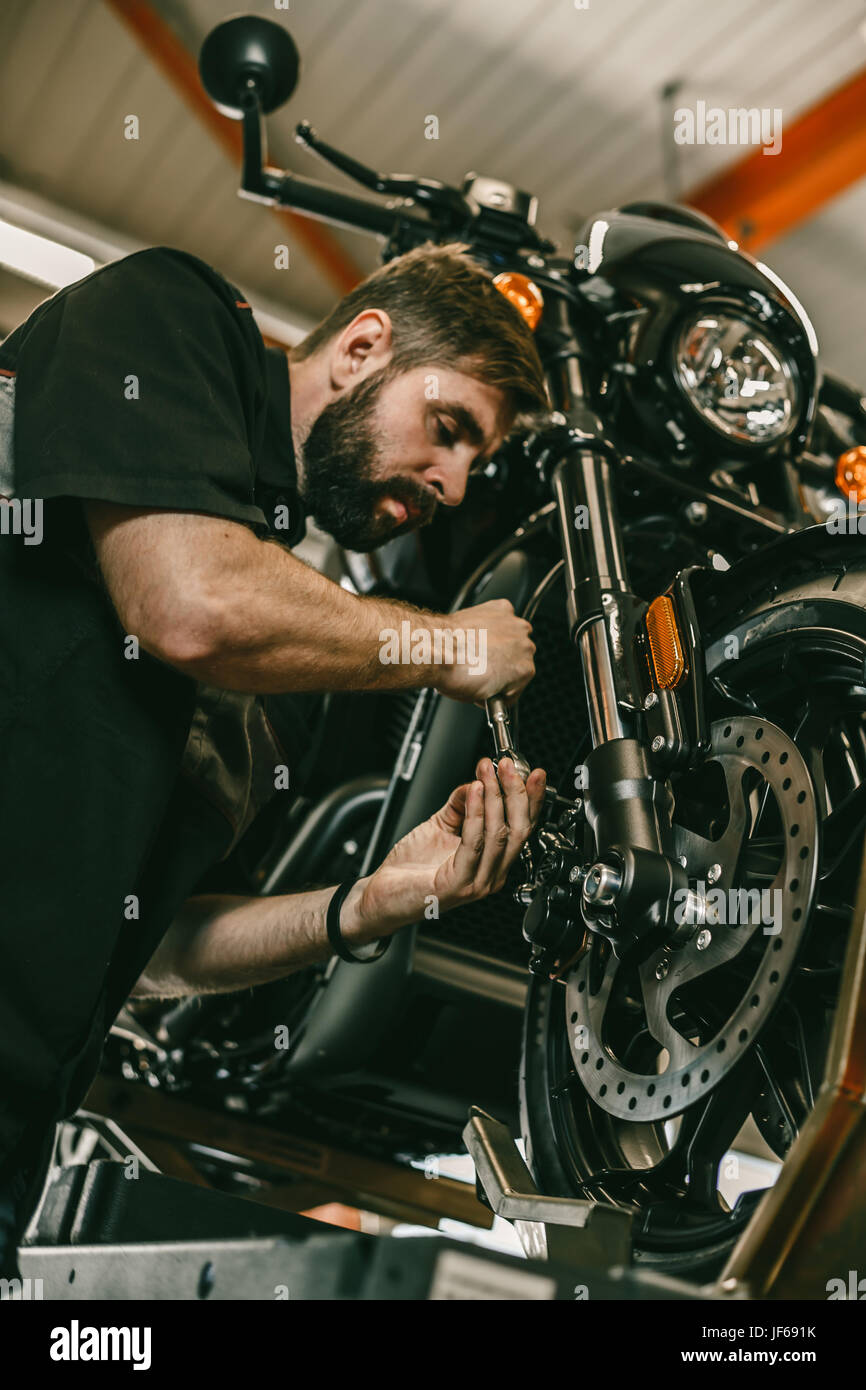 A professional mechanic unscrews the front wheel of a motorcycle. Bike ...