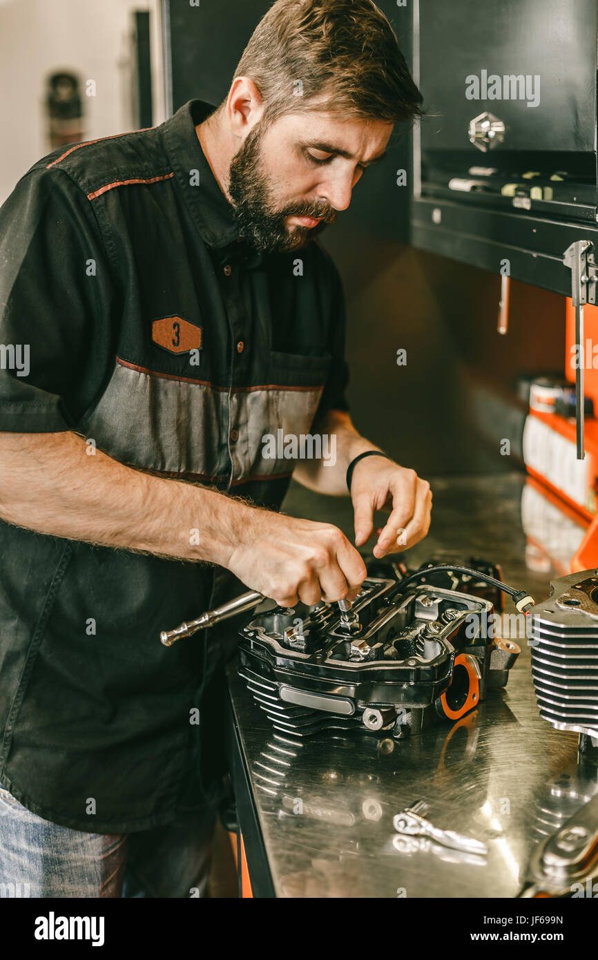 Motorcycle mechanic engine repair at service station. Motorcycle engine ...