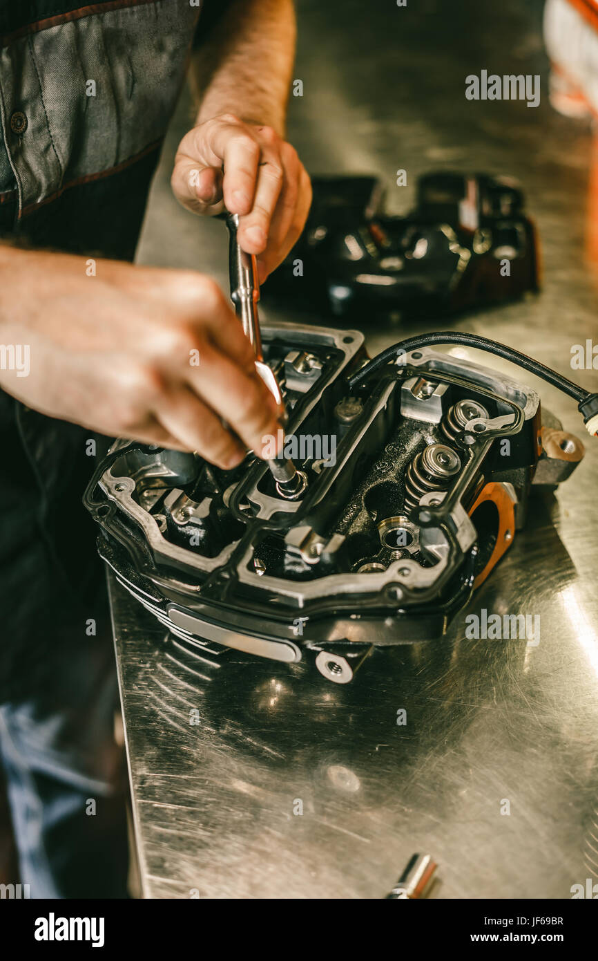 Closeup hands of motorcycle mechanic engine repair at service station ...