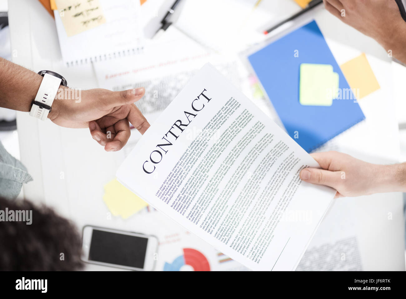 Overhead view of businessmen holding contract above table with papers ...