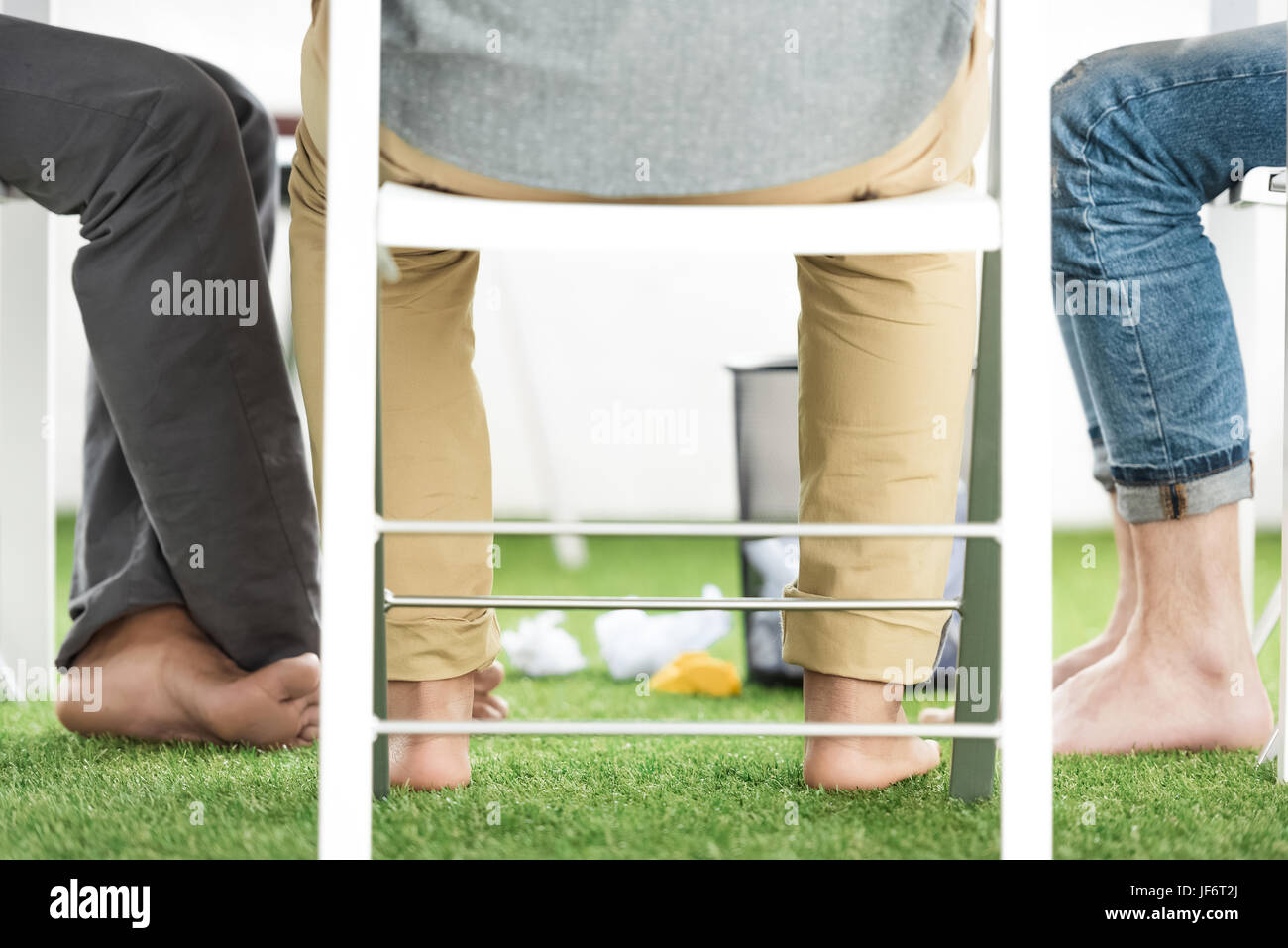 Partial view of barefoot businessmen sitting at table and working on ...