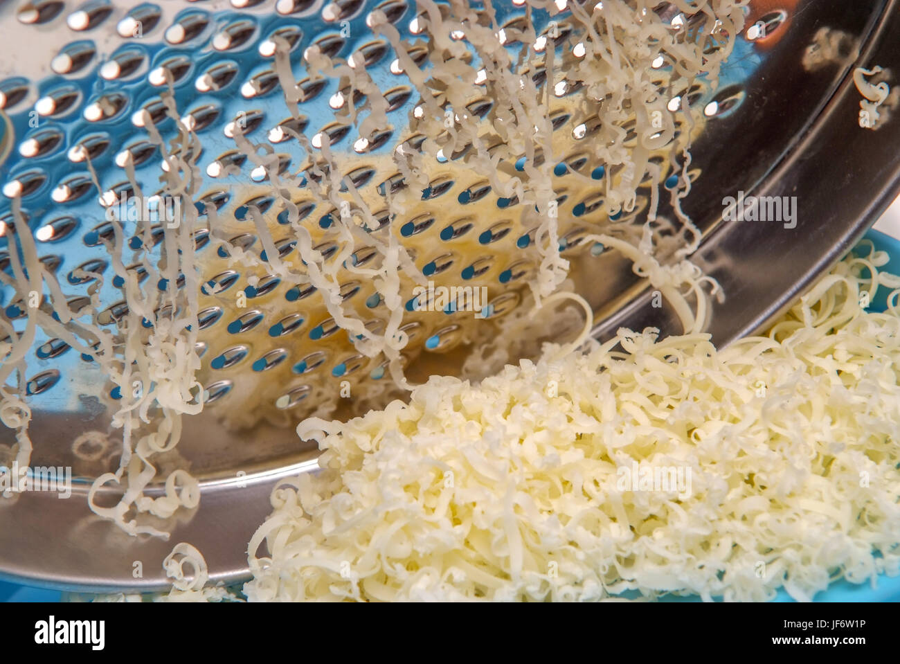 cheese being grated by a cheese grater close up Stock Photo - Alamy
