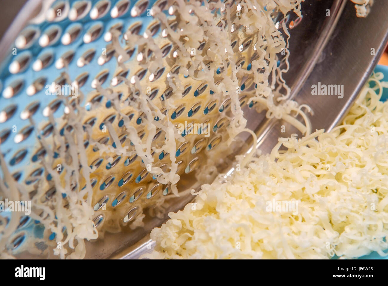 cheese being grated by a cheese grater close up Stock Photo - Alamy