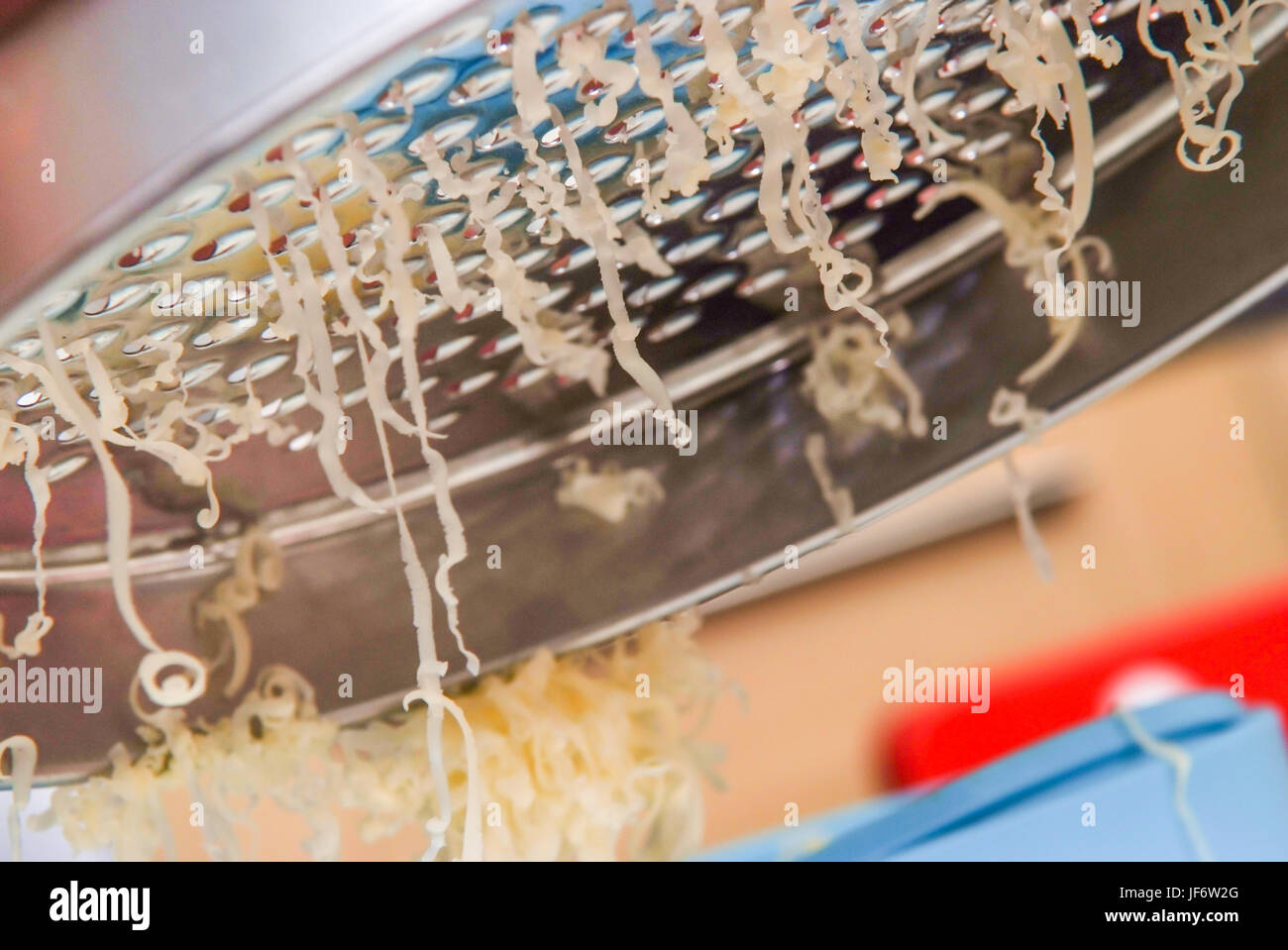 cheese being grated by a cheese grater close up Stock Photo - Alamy