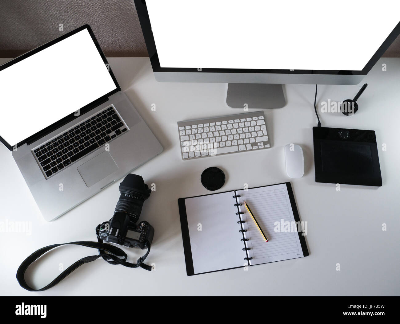Modern computers desk with technology tools and a paper note book seen ...