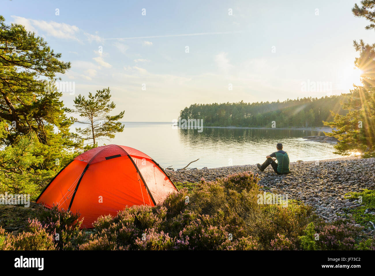 Young man camping by lake Stock Photo - Alamy