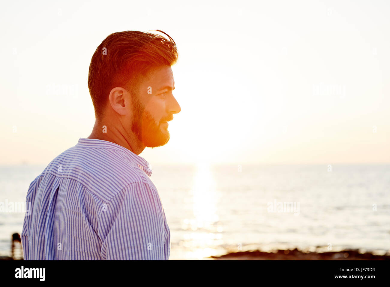 Man on beach at sunset Stock Photo - Alamy