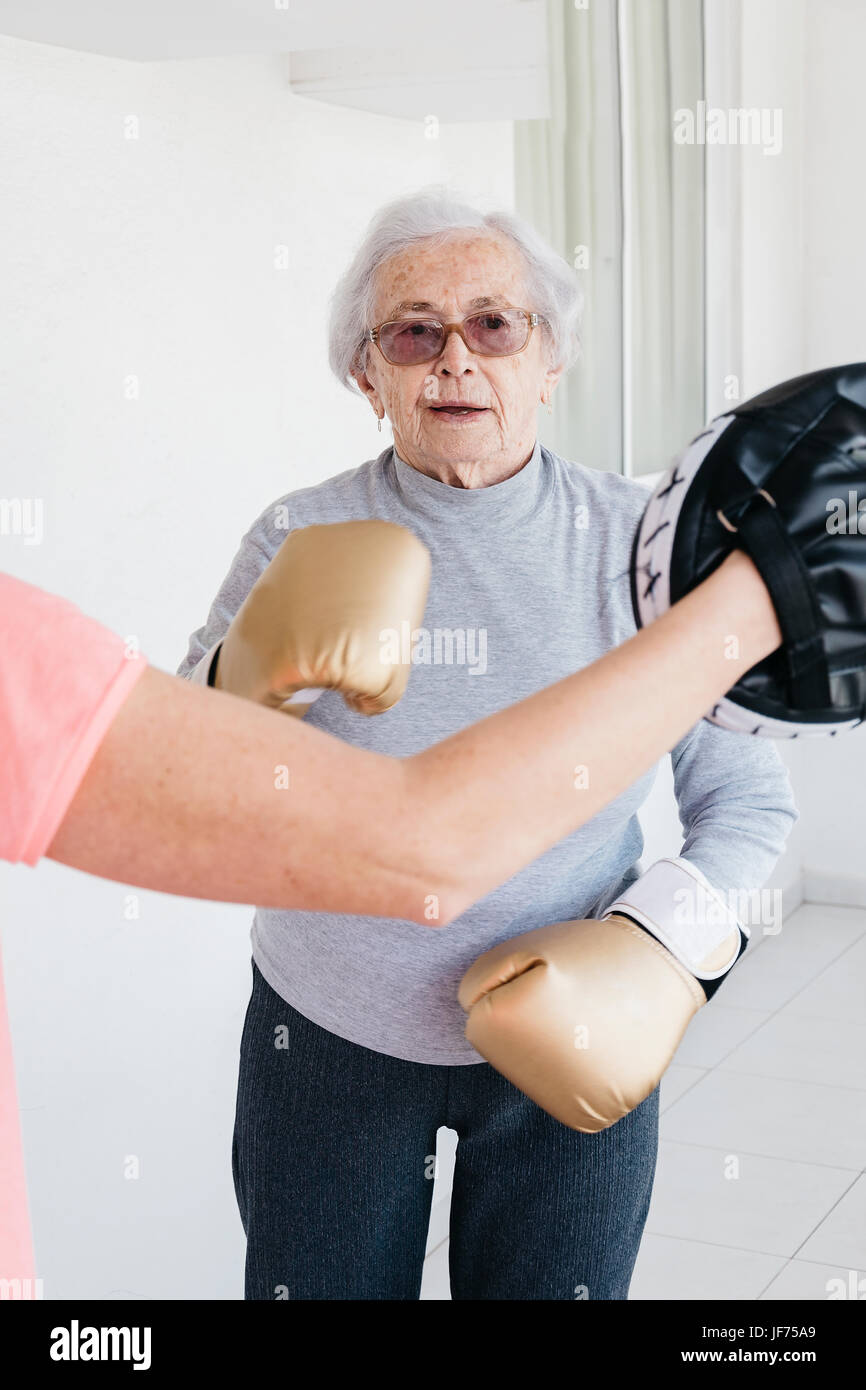 Senior woman boxing with fitness instructor Stock Photo - Alamy