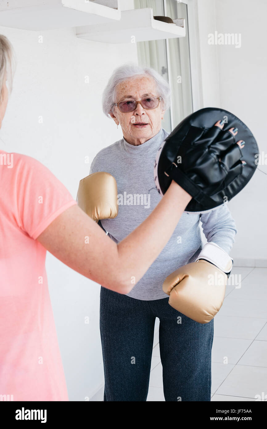 Senior woman boxing with fitness instructor Stock Photo - Alamy