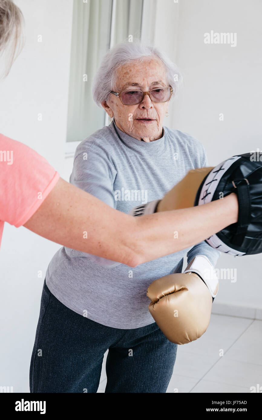 Senior woman boxing with fitness instructor Stock Photo - Alamy