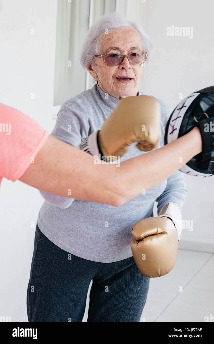 Senior woman boxing with fitness instructor Stock Photo - Alamy