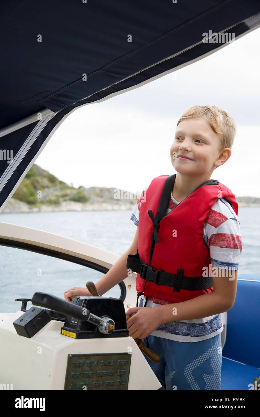 Boy driving motor boat Stock Photo - Alamy