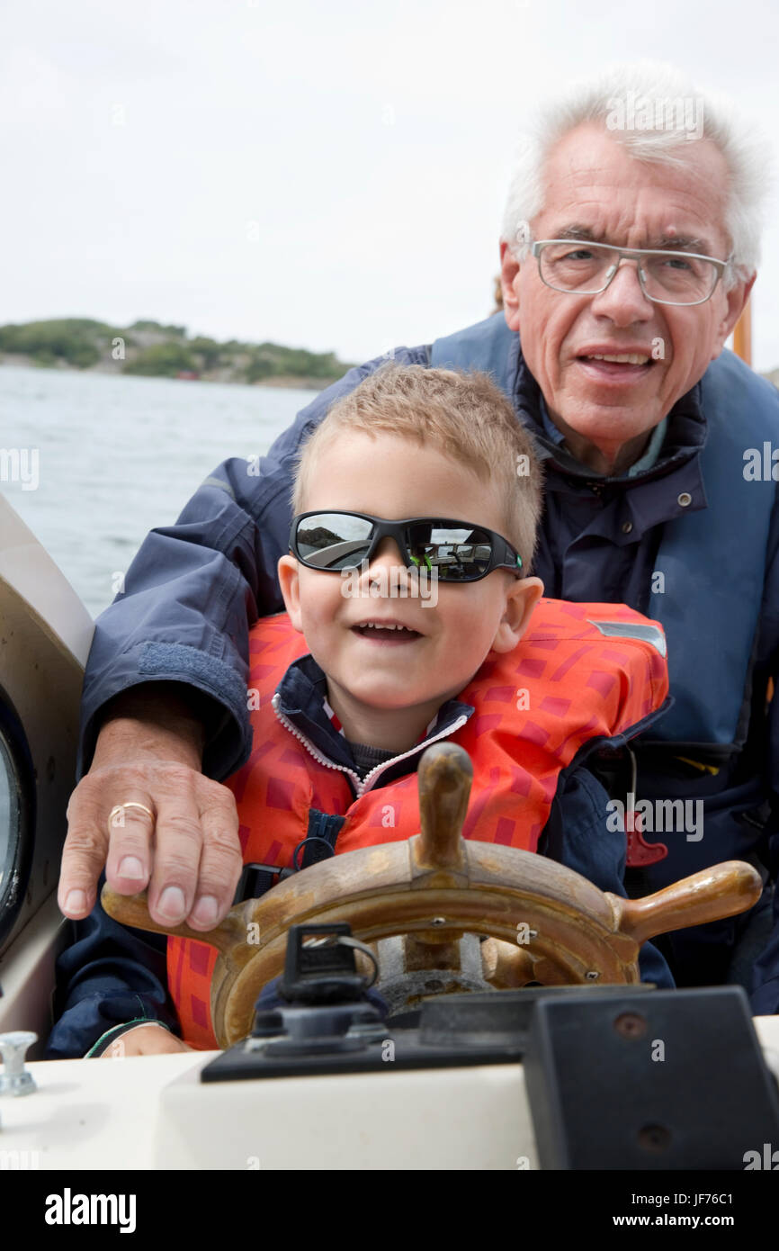 Boy driving boat with grandfather Stock Photo - Alamy