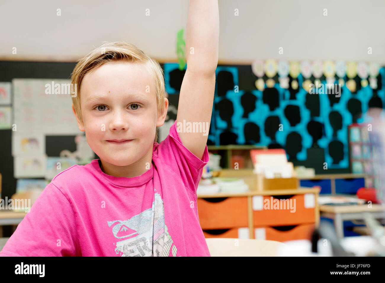Boy rising hand in classroom Stock Photo - Alamy