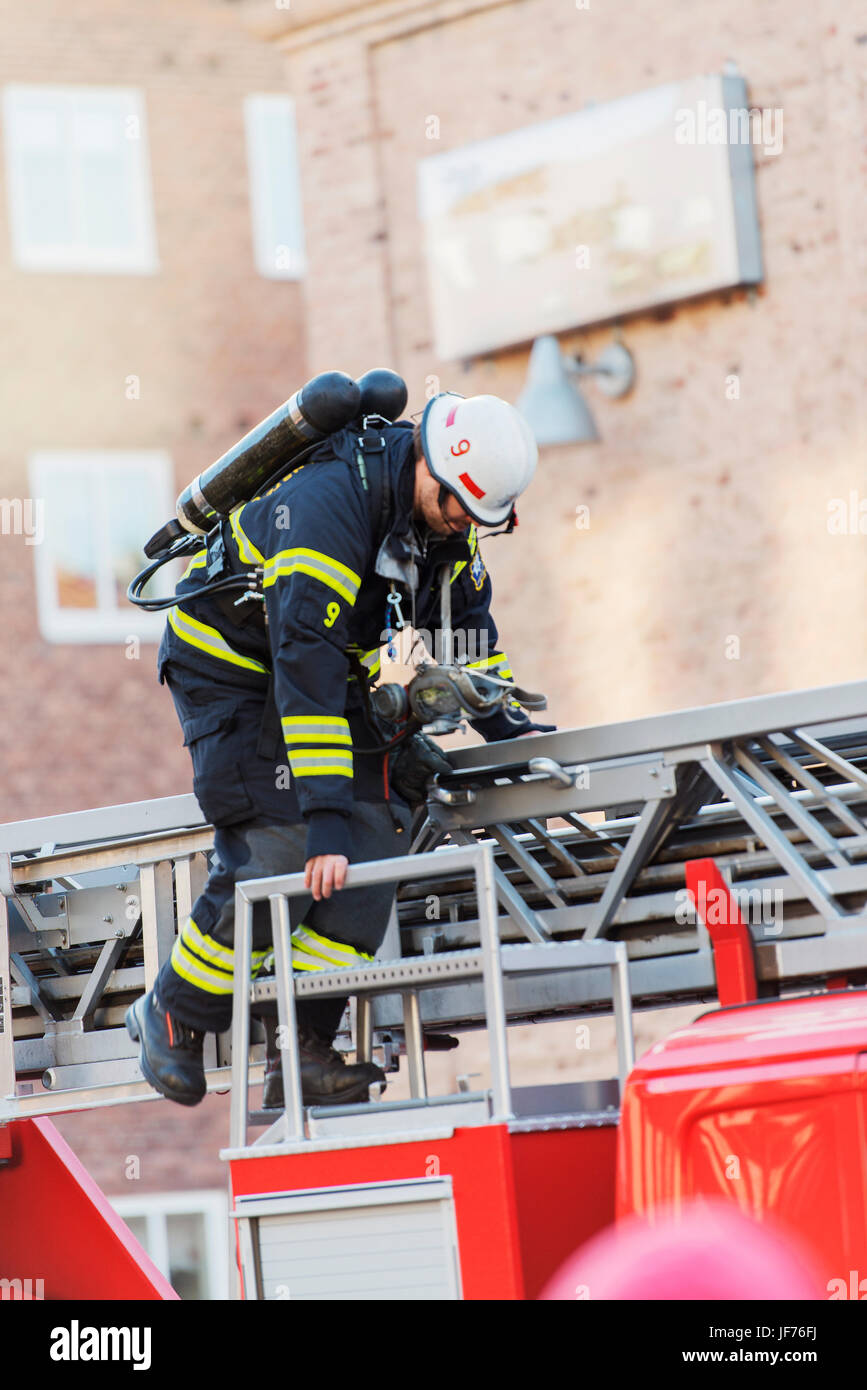 Firefighter standing on top of firetruck Stock Photo - Alamy