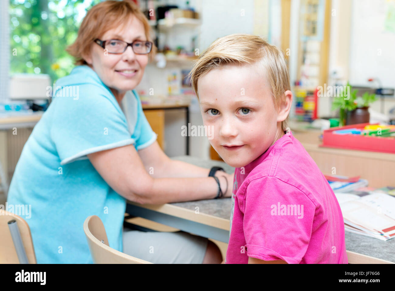 Boy and teacher sitting in classroom Stock Photo - Alamy