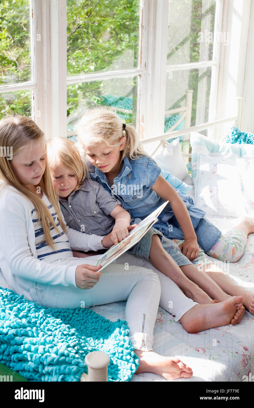 Three girls reading book Stock Photo - Alamy