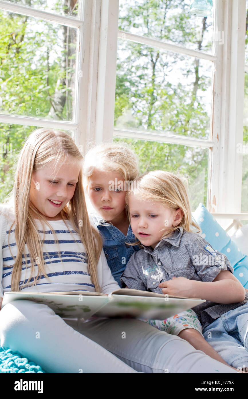Three girls reading book Stock Photo - Alamy