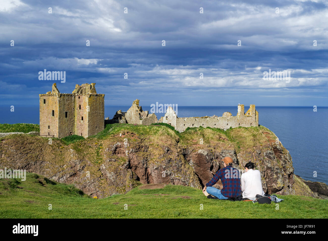 Tourists looking at Dunnottar Castle, ruined medieval fortress near ...